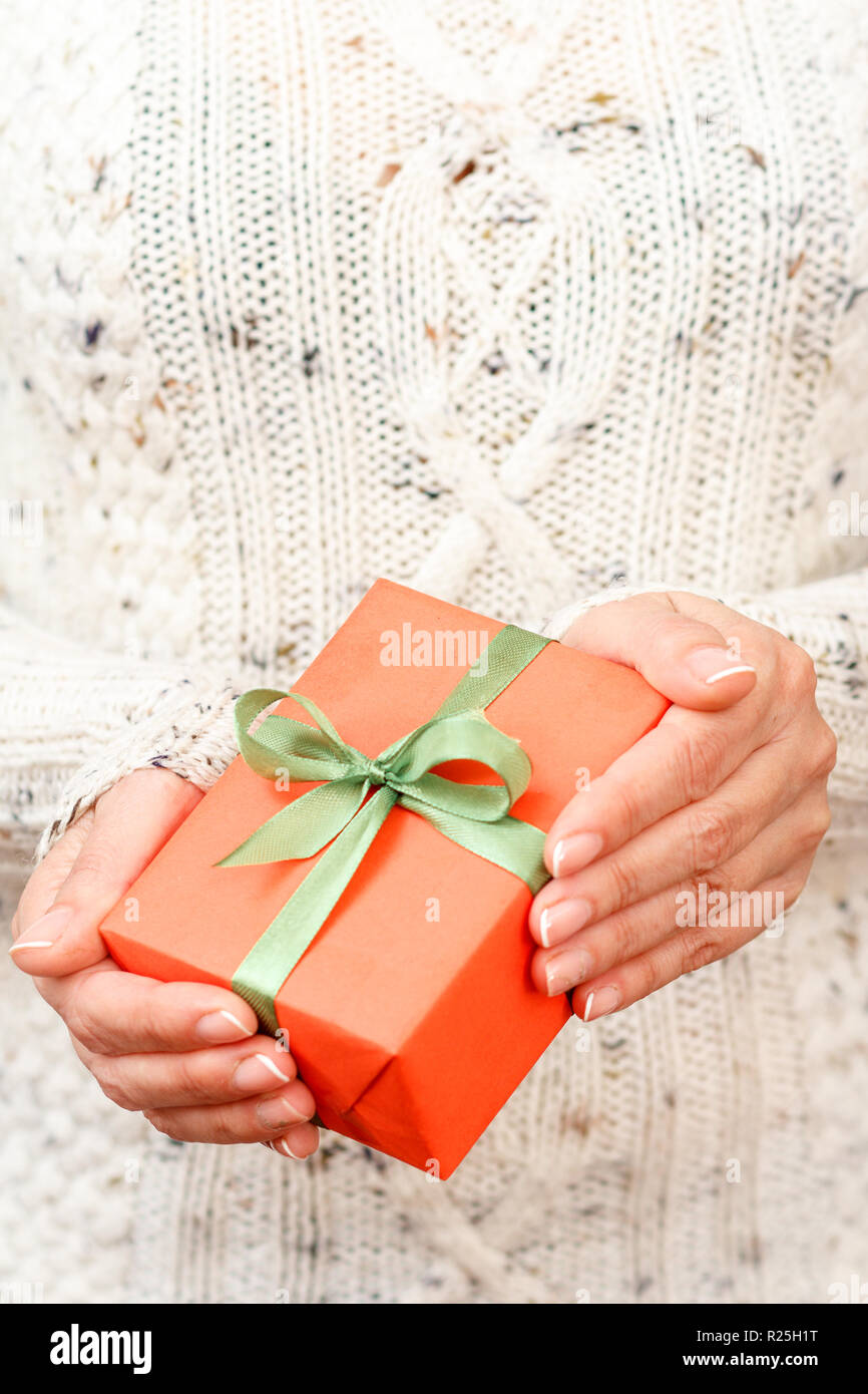 Woman holding a gift box tied with a green ribbon in her hands. Shallow ...