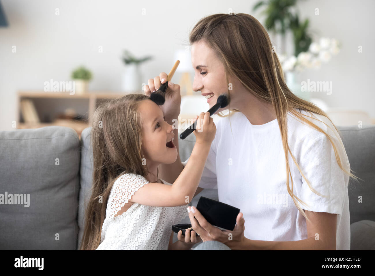 Smiling mom and happy kid daughter doing makeup together Stock Photo ...