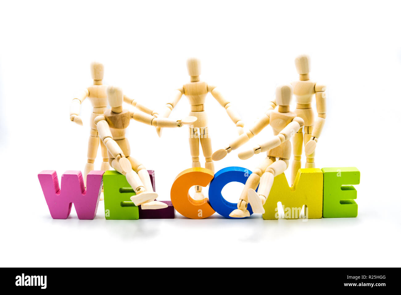 Wooden figures posing as business men behind the word WELCOME, high key ...