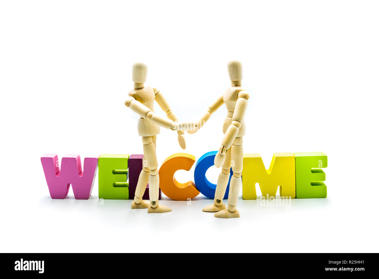 Wooden figures posing as business men shaking hands in front of the ...