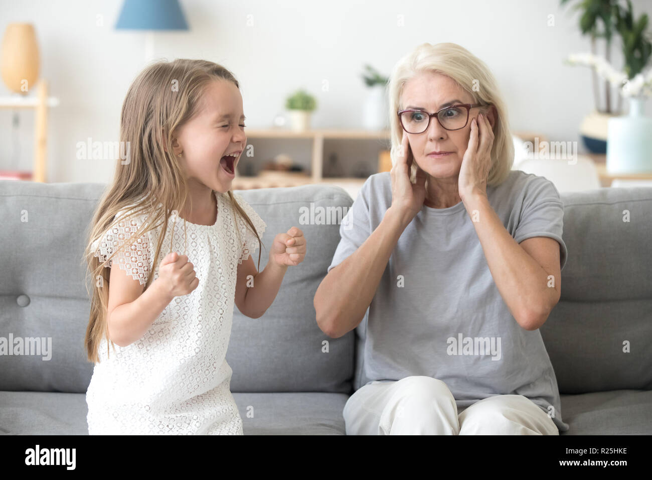 Shocked grandma closing ears not to hear stubborn granddaughter Stock ...