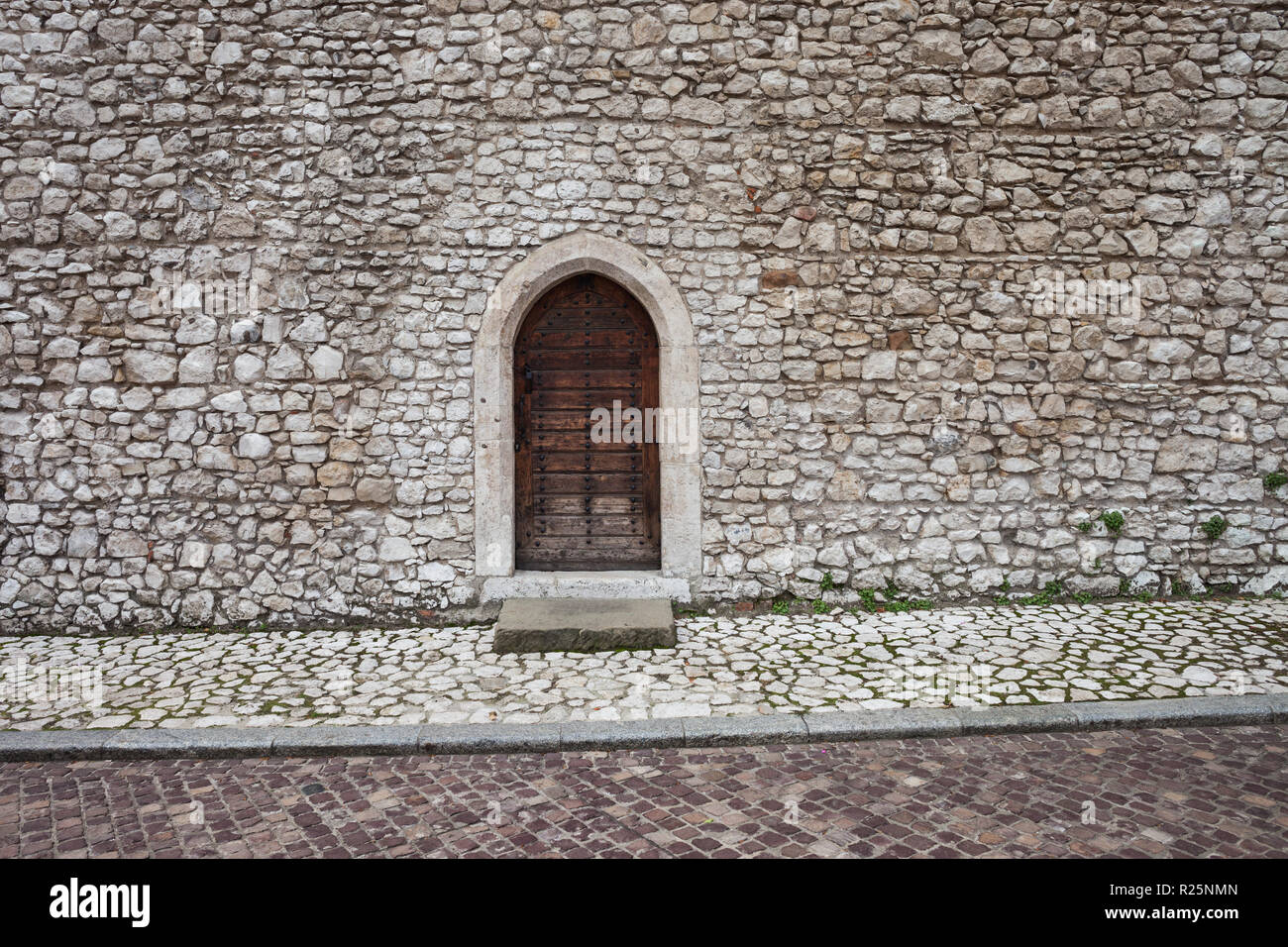 Medieval castle stone wall with arched wooden door and sidewalk Stock ...