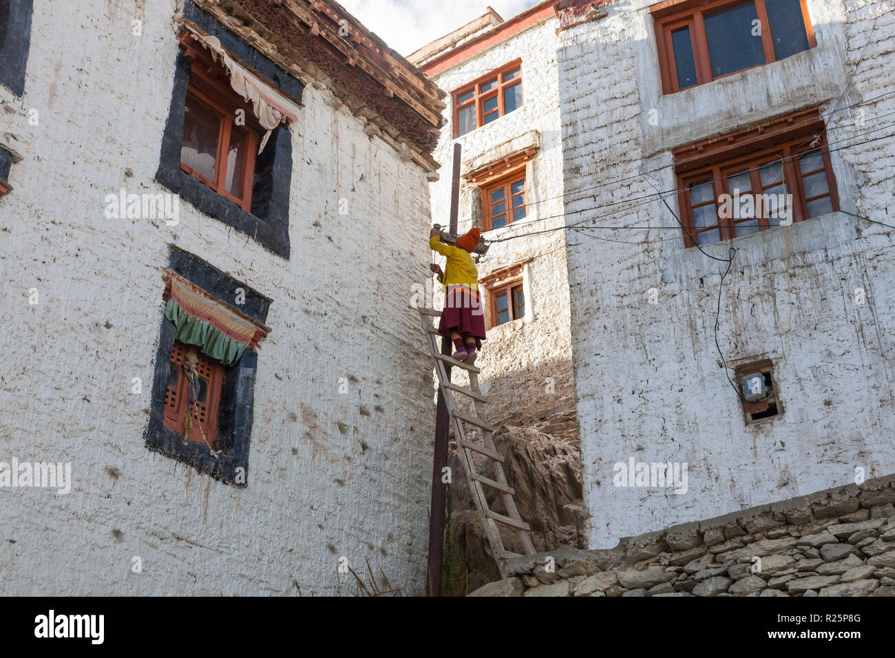 Buddhist monk standing on the wooden ladder and fixing something ...