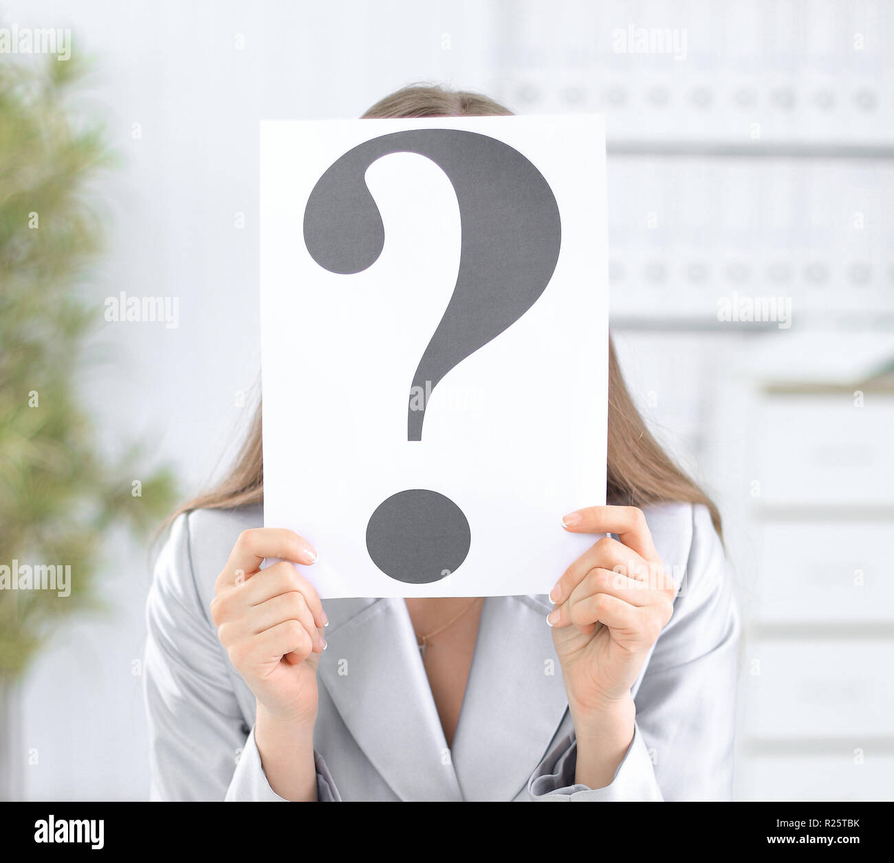 young business woman holding a question mark ,sitting behind a Desk ...