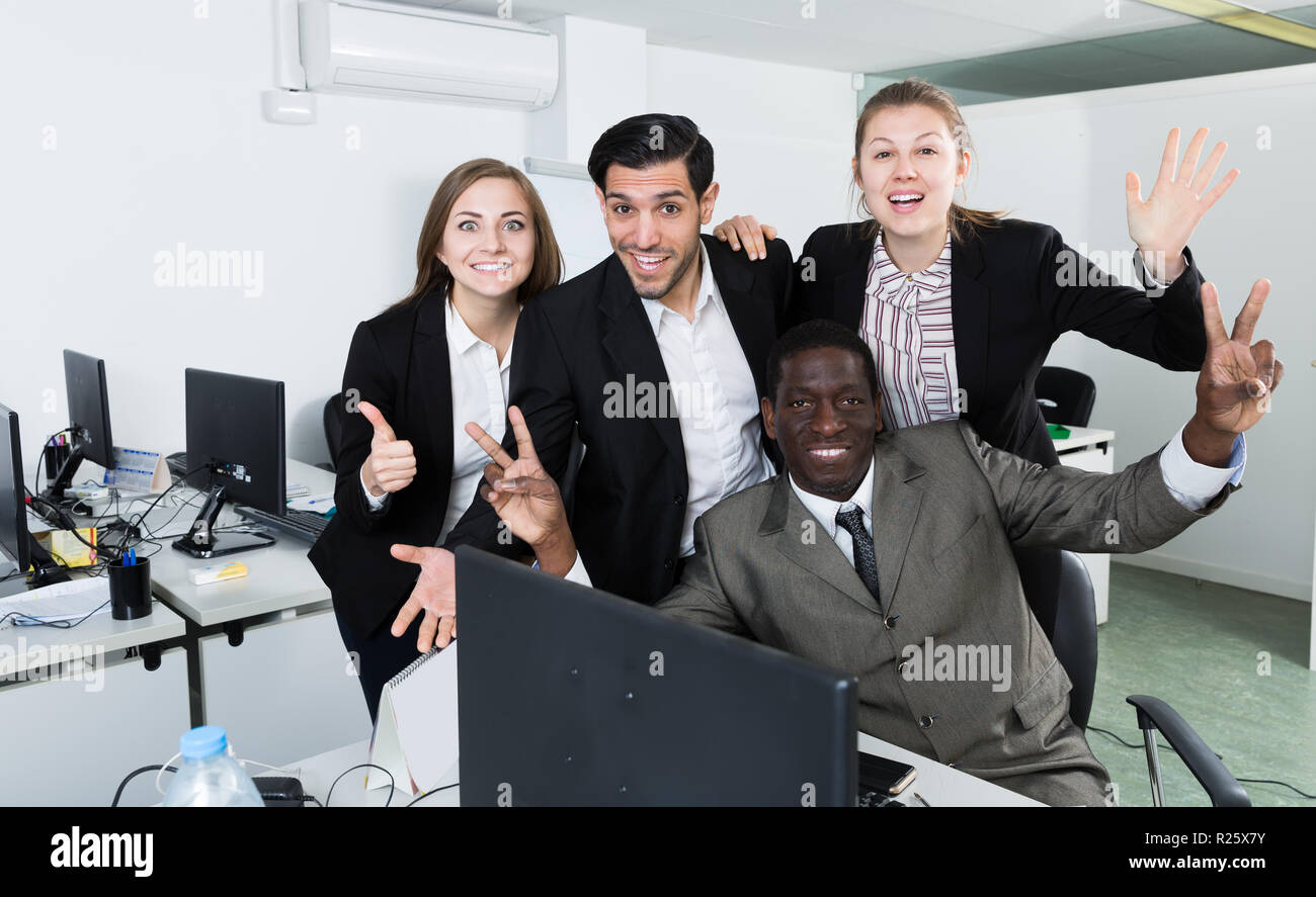 Portrait of friendly team of employees rejoicing and waving their hands ...
