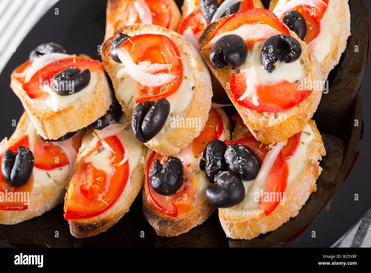Healthy toasts with creamy sauce, tomatoes and black olives served on ...