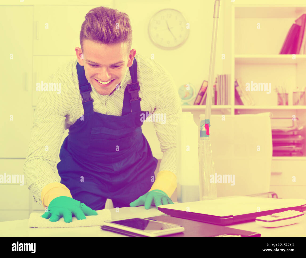 Cheerful friendly male professional janitor dusting in modern office ...