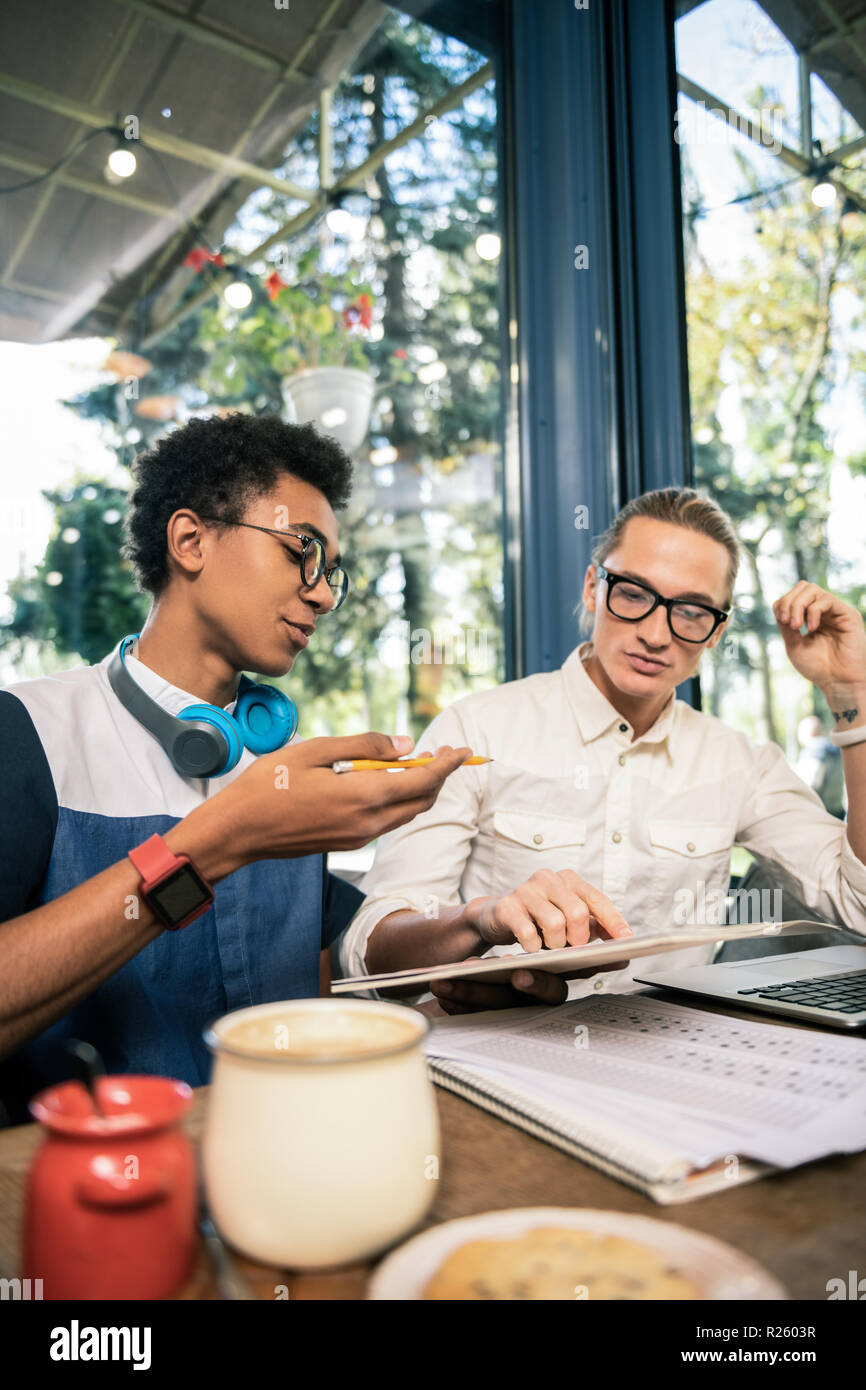 Nice Afro American man asking his friend about the task Stock Photo - Alamy