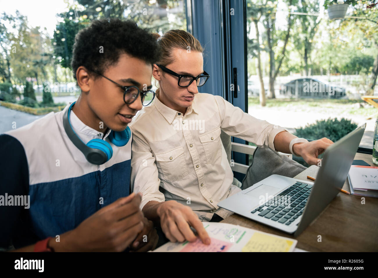 Nice serious man pointing at his friends notes Stock Photo - Alamy
