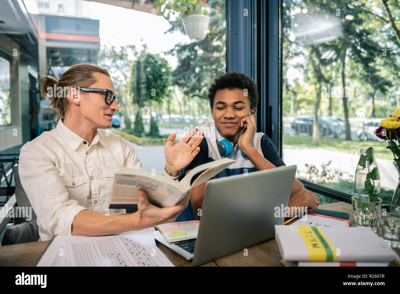 Smart young tutor holding a big book Stock Photo - Alamy