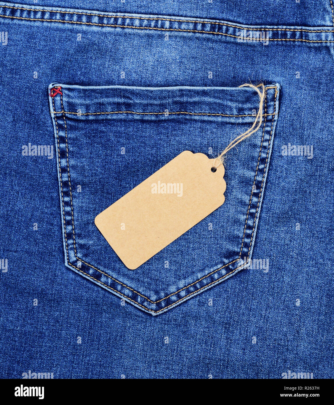 Brown paper blank price tag on rope against the back pocket of blue ...