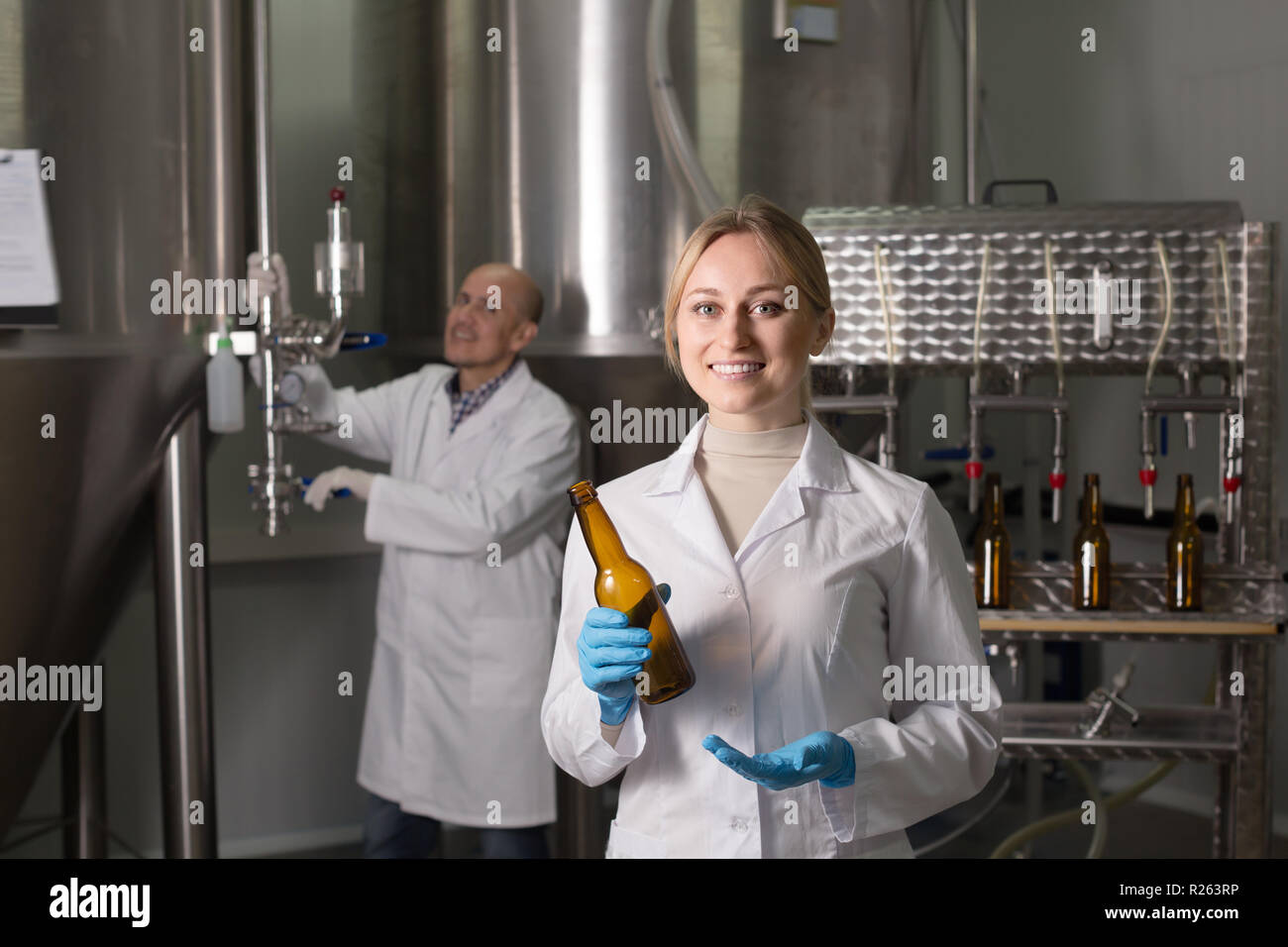Portrait of laughing young woman employee in modern beer production ...