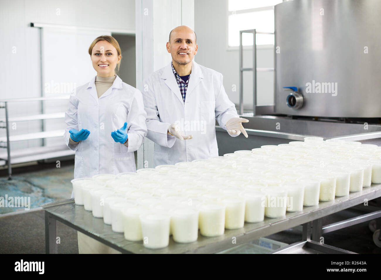 Portrait of man and woman dressed in white coats working on cottage ...