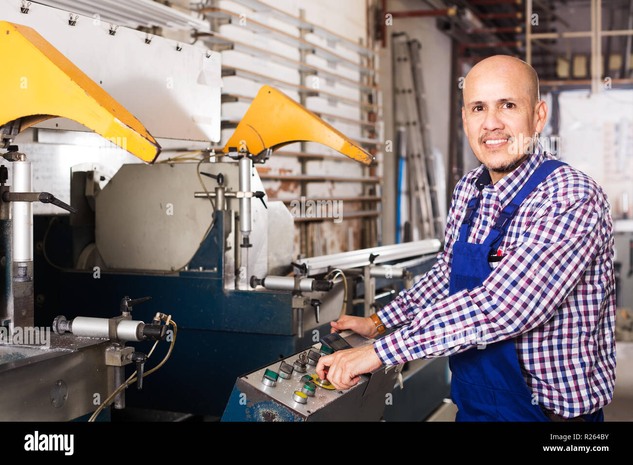 Positive workman in uniform working on lathe machine at factory Stock ...