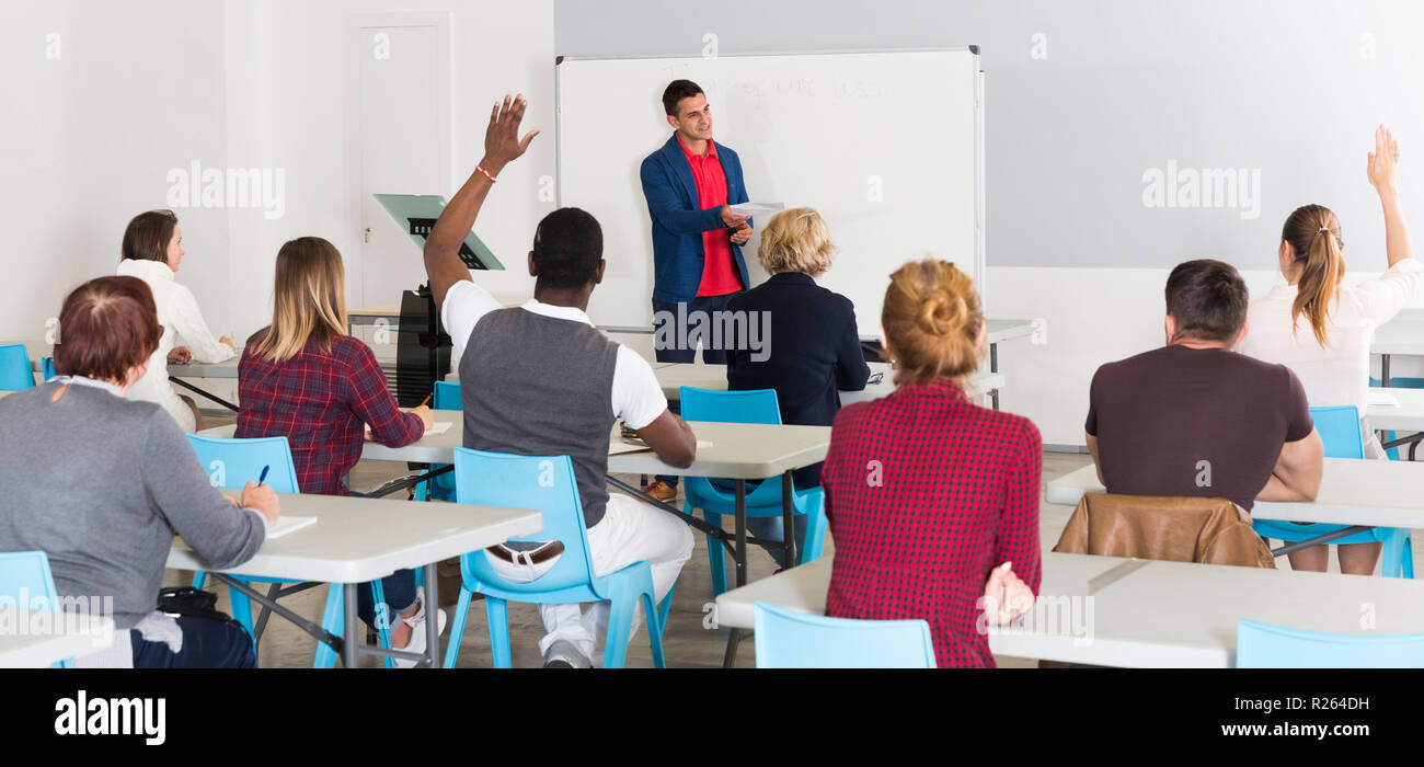 Confident male student answering at whiteboard in front group of ...