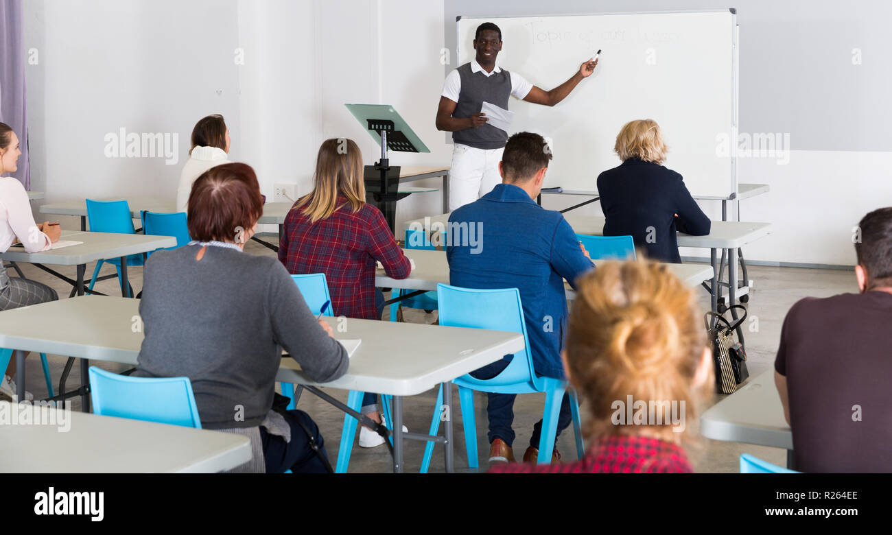 Friendly African American man lecturing to attentive adult students at ...