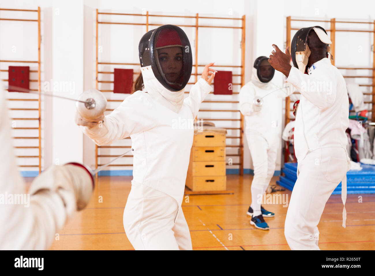 Sporty active woman fencer practicing fencing combination in training ...