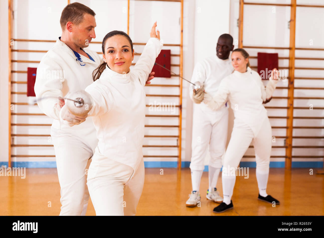 Female fencer practicing movements with trainer at fencing workout ...