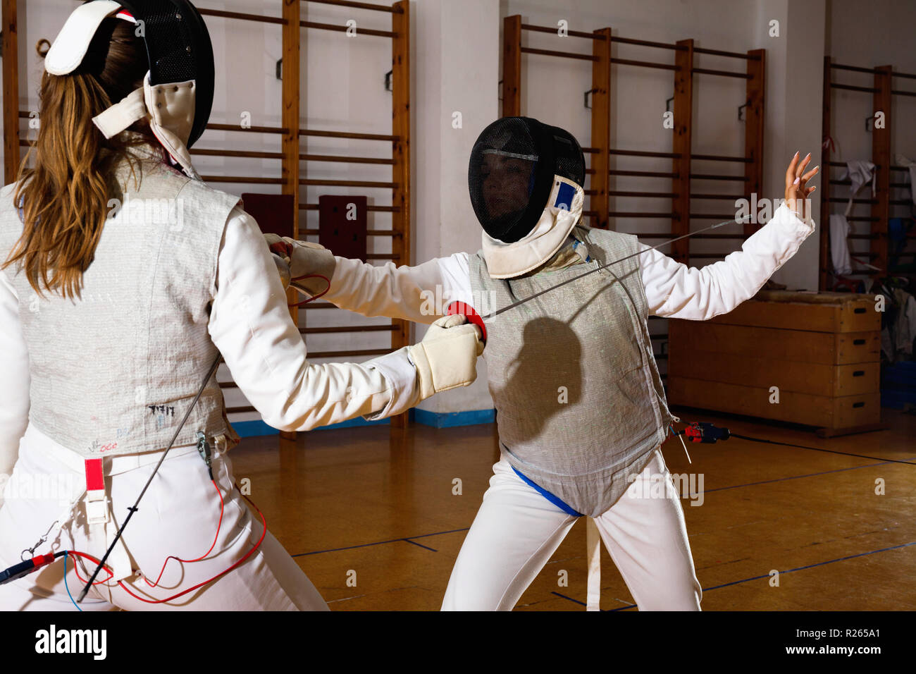 Two glad positive female fencers exercising movements in duel at ...