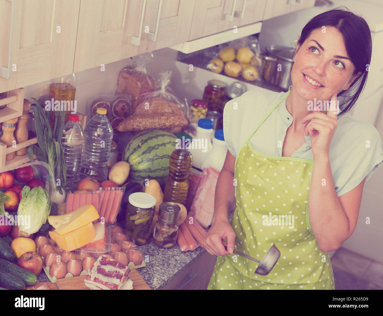 Portrait of cheerful female who is readying for cooking new recipe at ...
