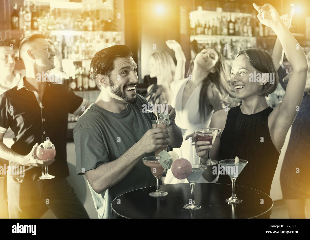 Glad smiling man with woman are drinking cocktails on corporate party ...