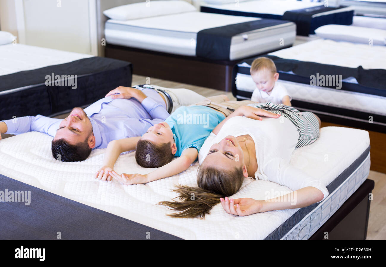 Happy family testing mattress in store, lying on back Stock Photo - Alamy