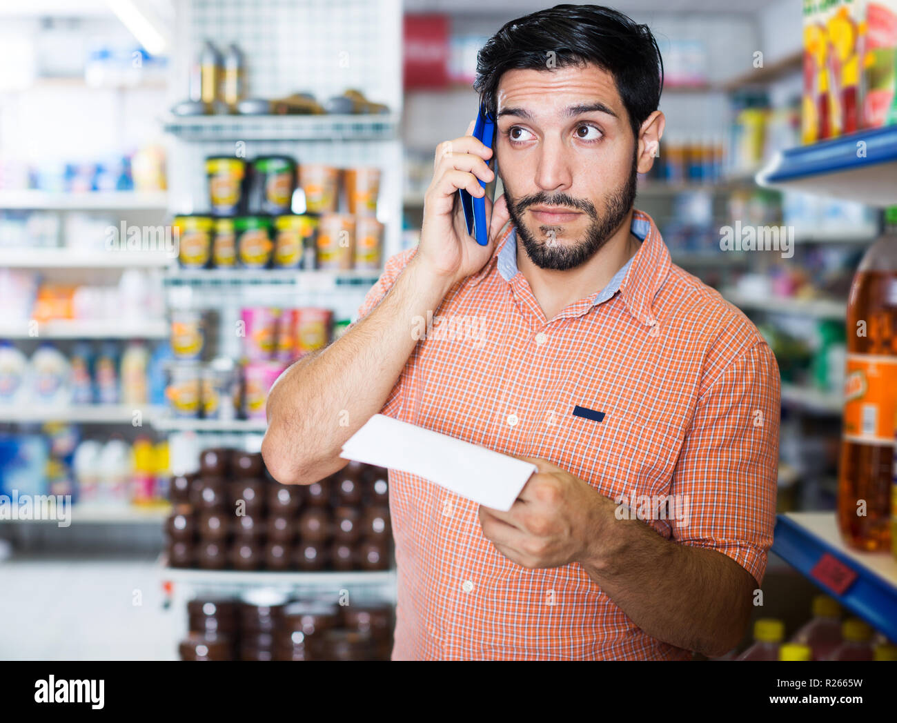 man customer who is standing with note list and talking phone in ...