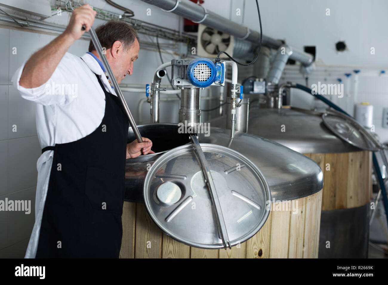 Brewer is controls the brewing process near reservoir with beer indoor ...