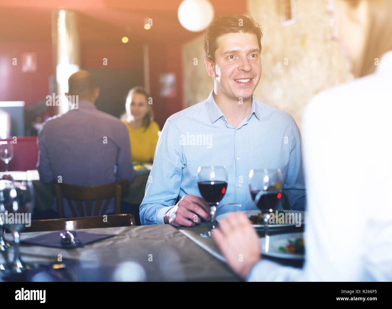 Smiling boyfriend with female on dinner with wine in restaurant Stock ...