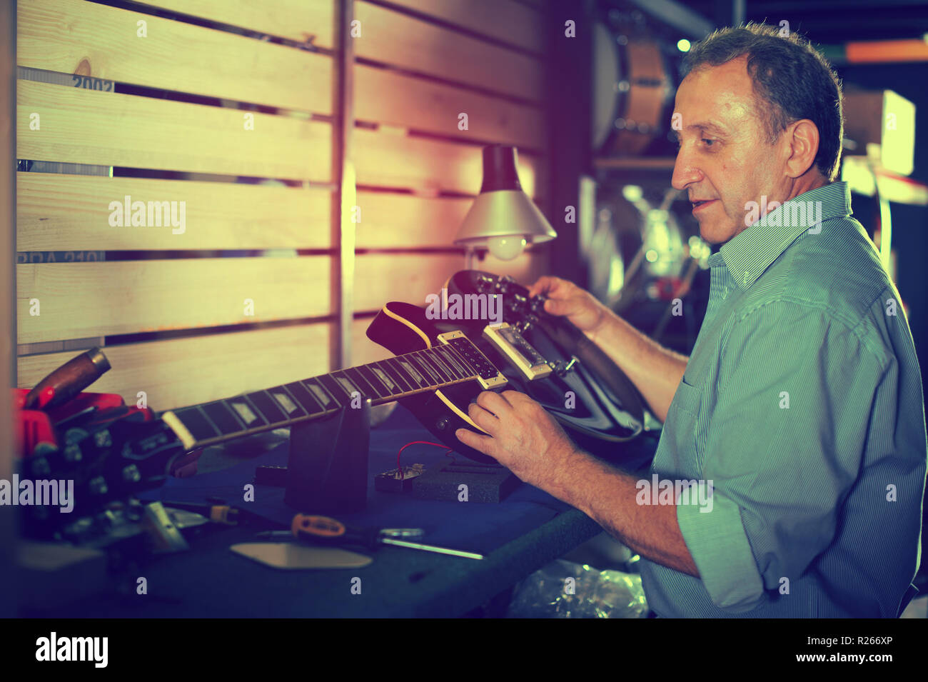 Adult music master is repairing guitar in his workshop Stock Photo - Alamy