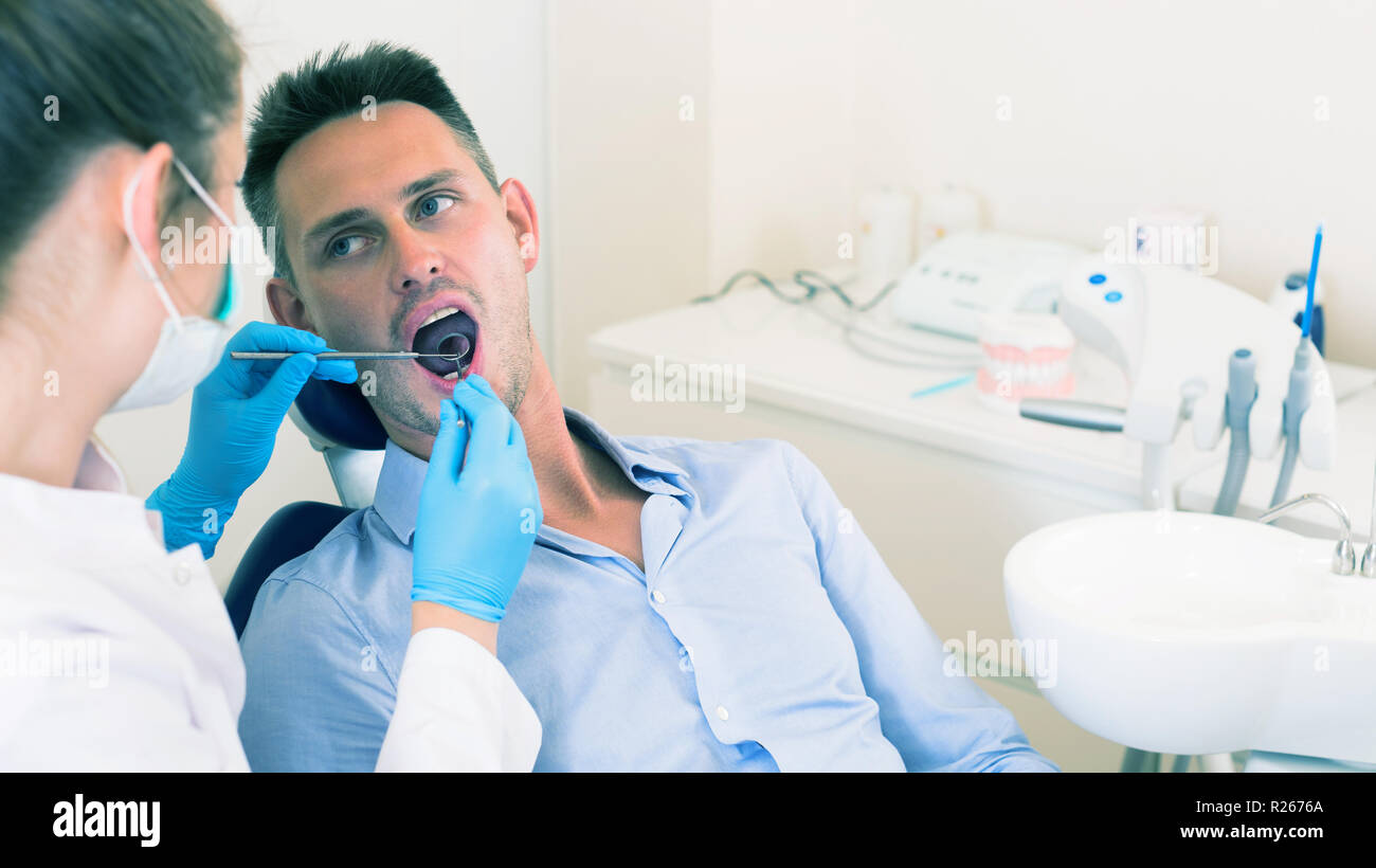 Young doctor in uniform is taking visional inspection of an adult ...