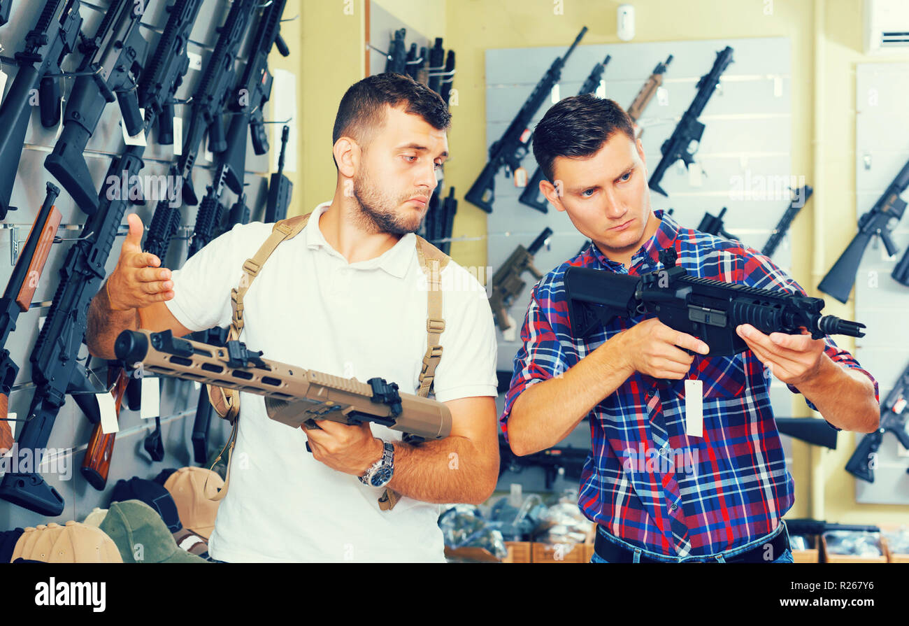 two young male friends choosing air-powered gun in army market Stock ...