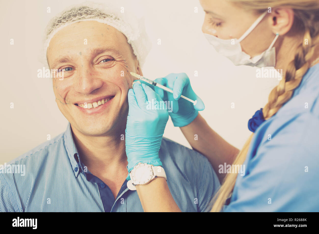 Female doctor is doing injection to patient in skin of face in estetic ...