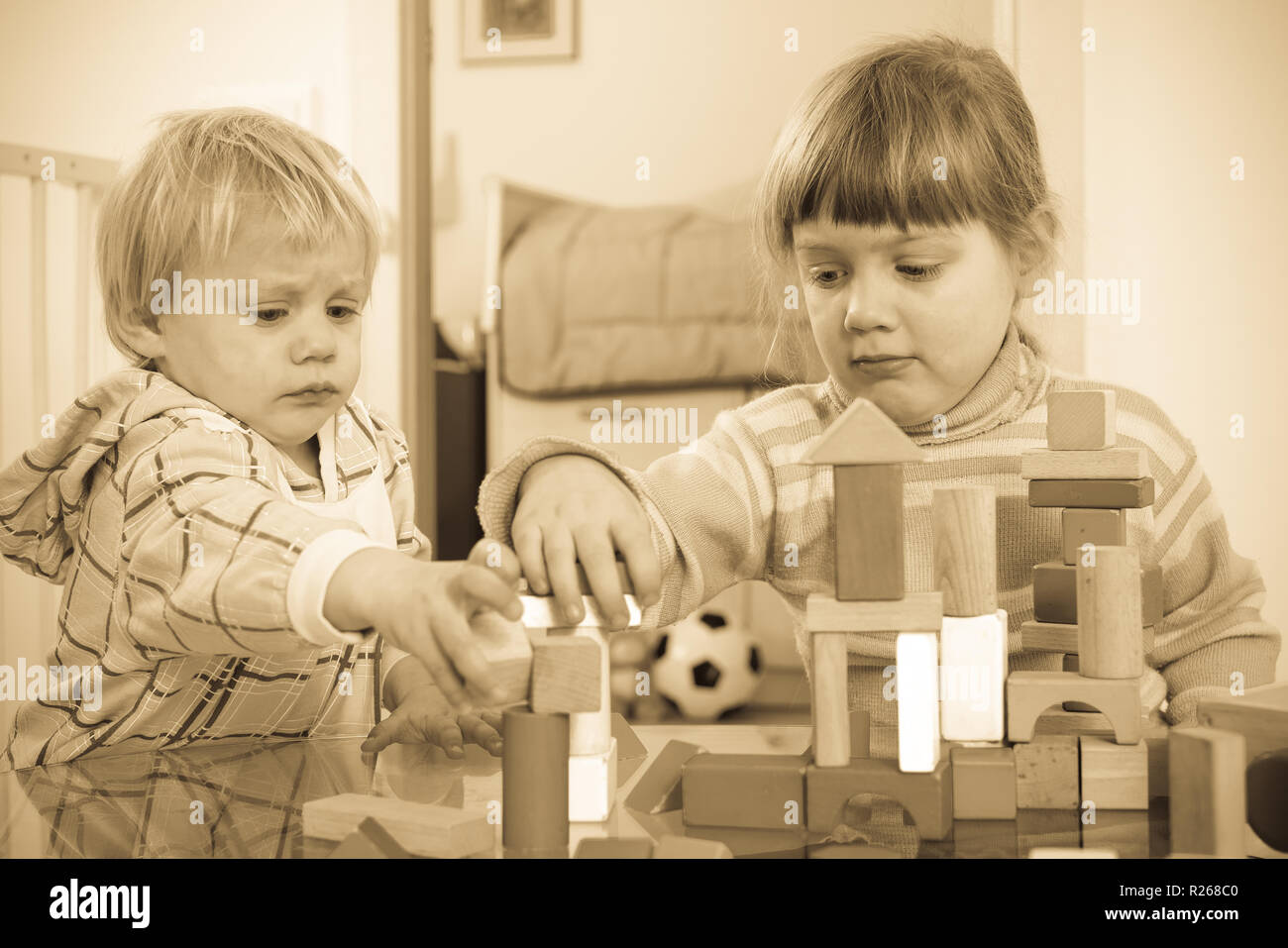 Two serious children playing with wooden blocks in home interior Stock ...