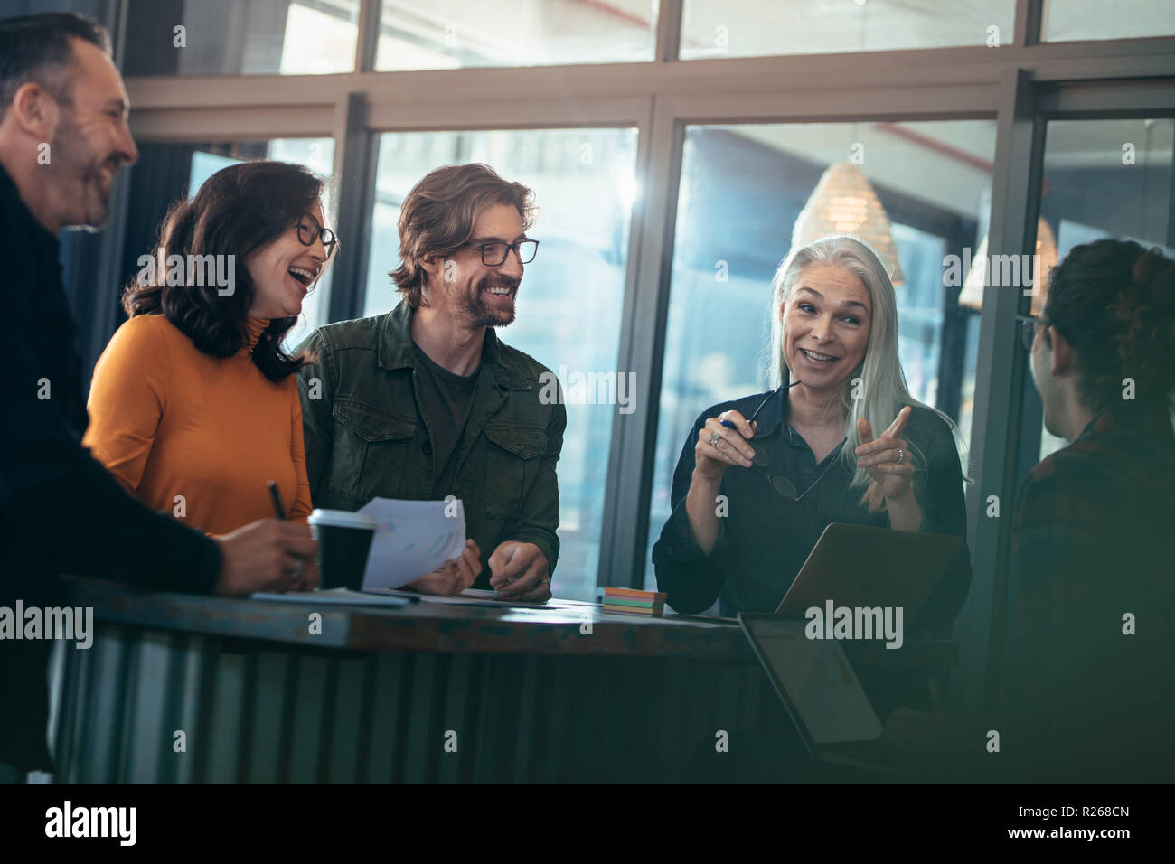 Smiling senior business woman discussing with colleagues during meeting ...