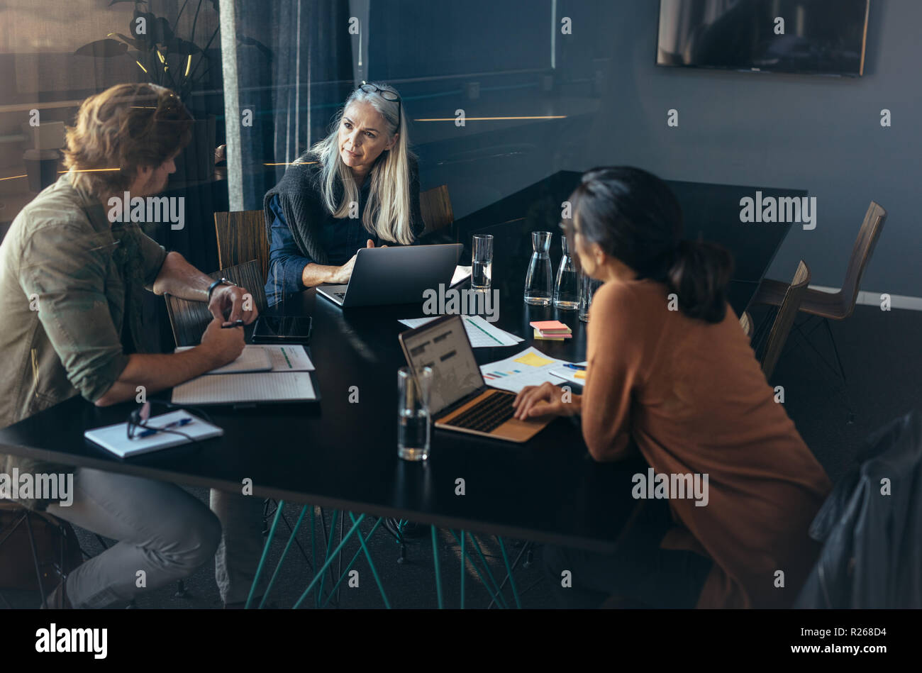 Three professionals sitting around a table and discussing work ...