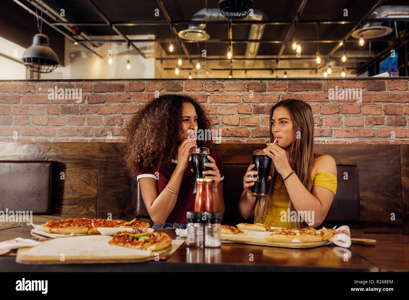 Two multi-ethnic women sitting at restaurant having lunch together ...