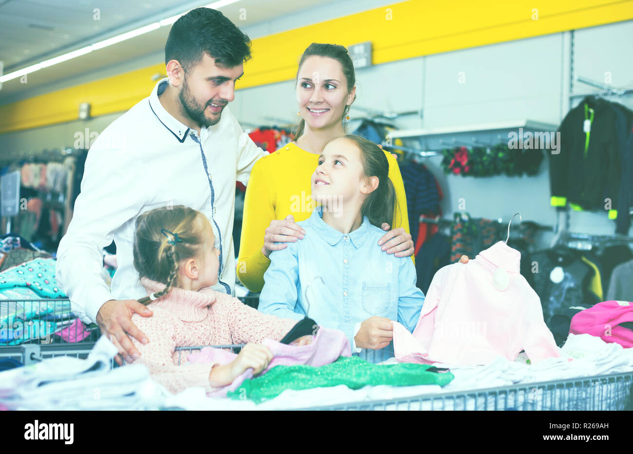 smiling family with two little girls choosing new clothes in mall Stock ...