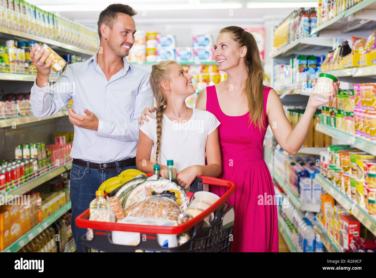 Happy family customers standing with purchases in shopping cart in ...