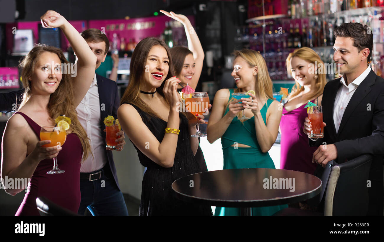 Happy positive colleagues dancing on corporate party with cocktails in ...