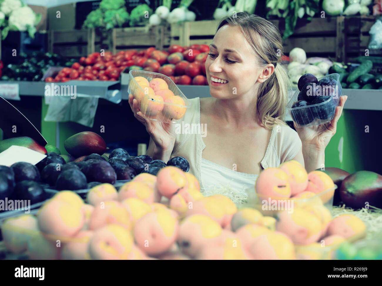happy young female customer choosing plums on fruit market Stock Photo ...