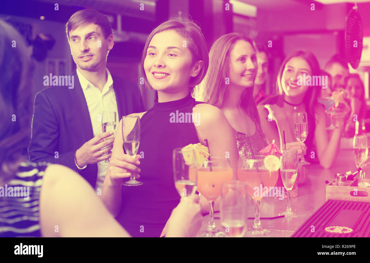 People are talking at the bar counter with cocktails in their hands ...