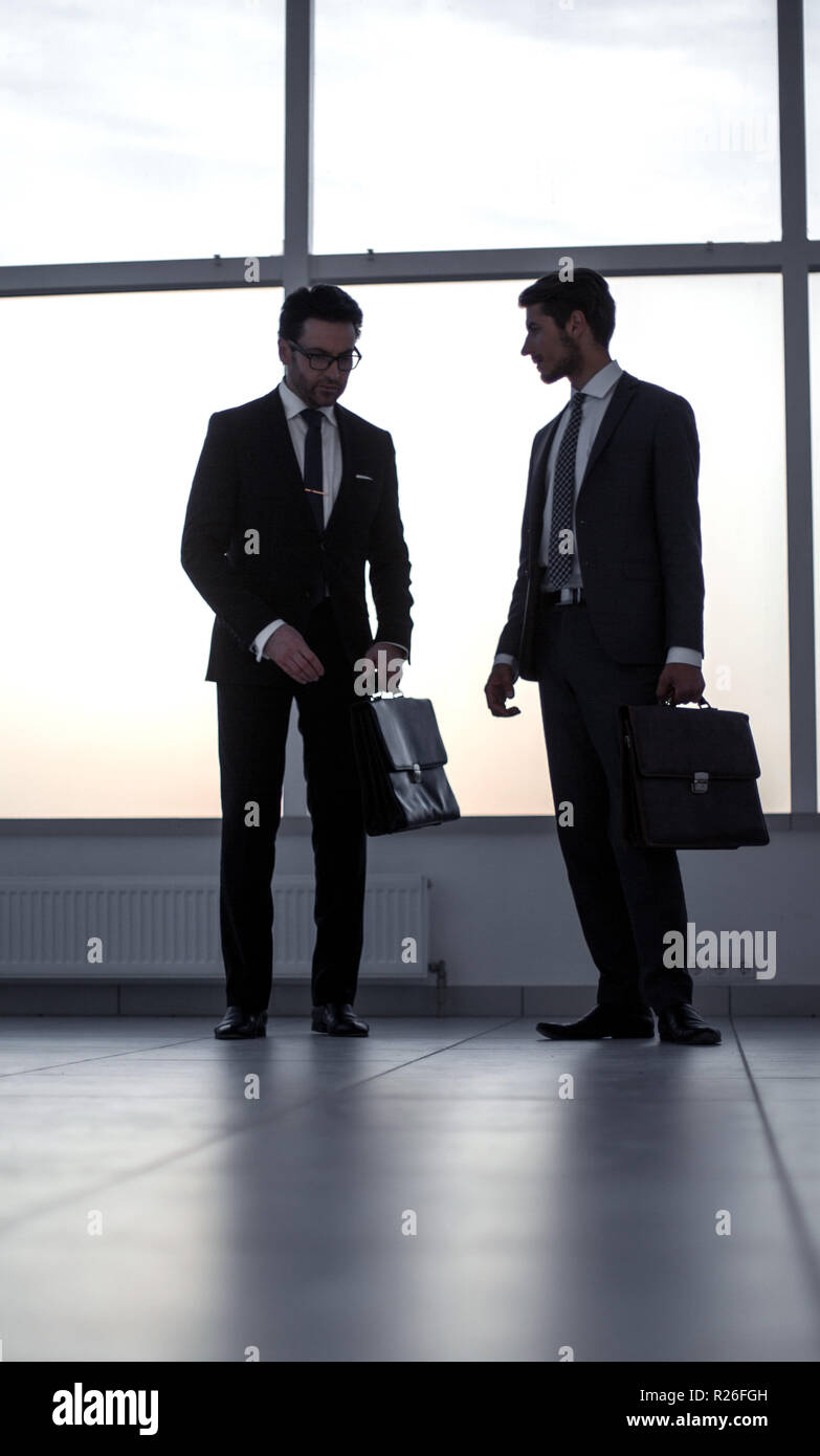 two businessmen talking standing in the office hall Stock Photo - Alamy