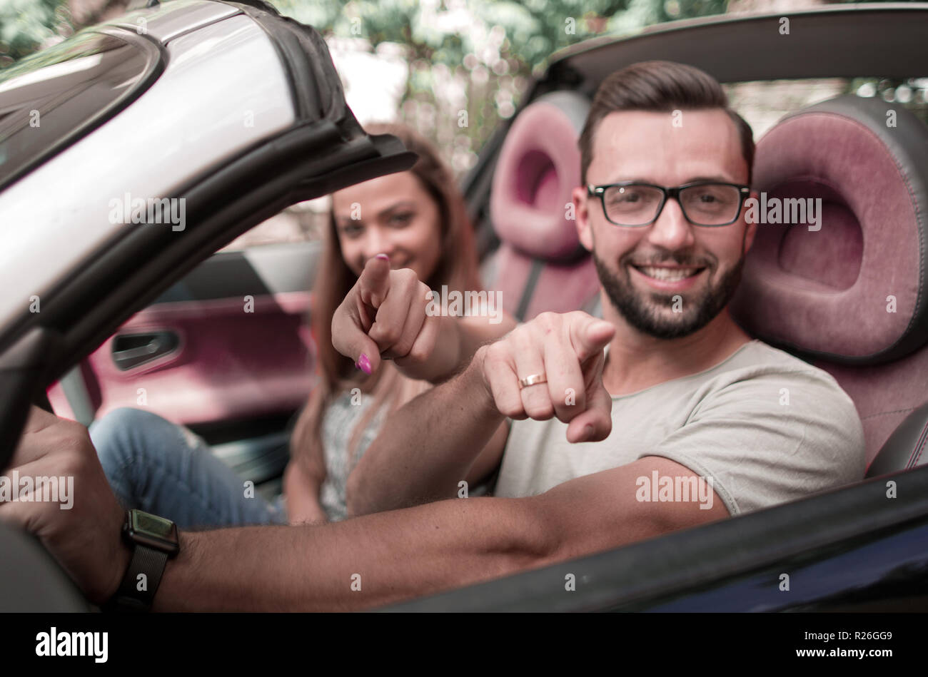 loving couple in a convertible car pointing at you Stock Photo - Alamy