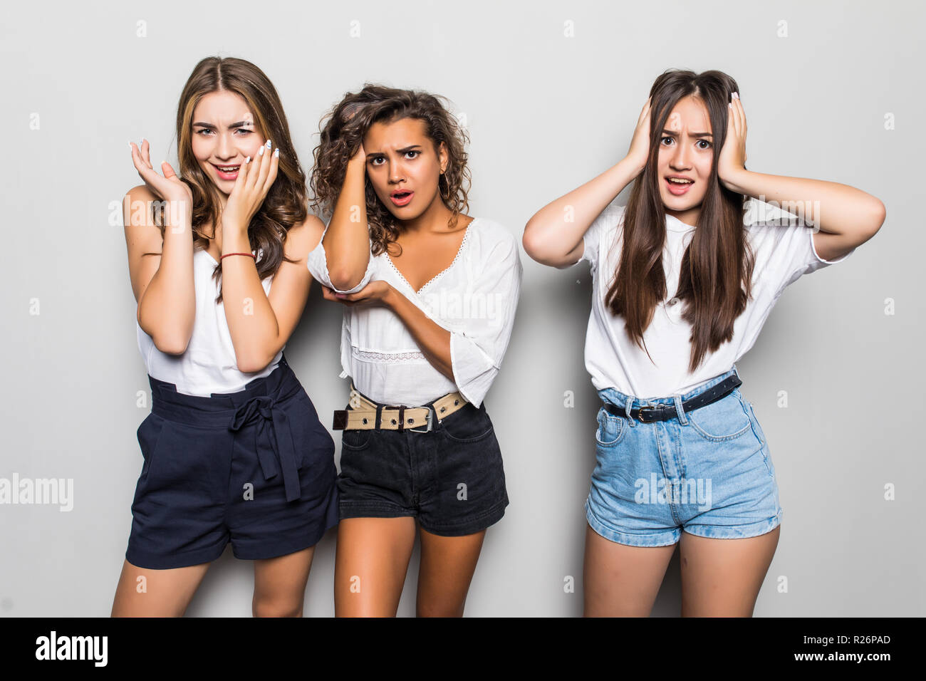 Portrait of shocked three girls with wide open mouth eyes and long hair ...