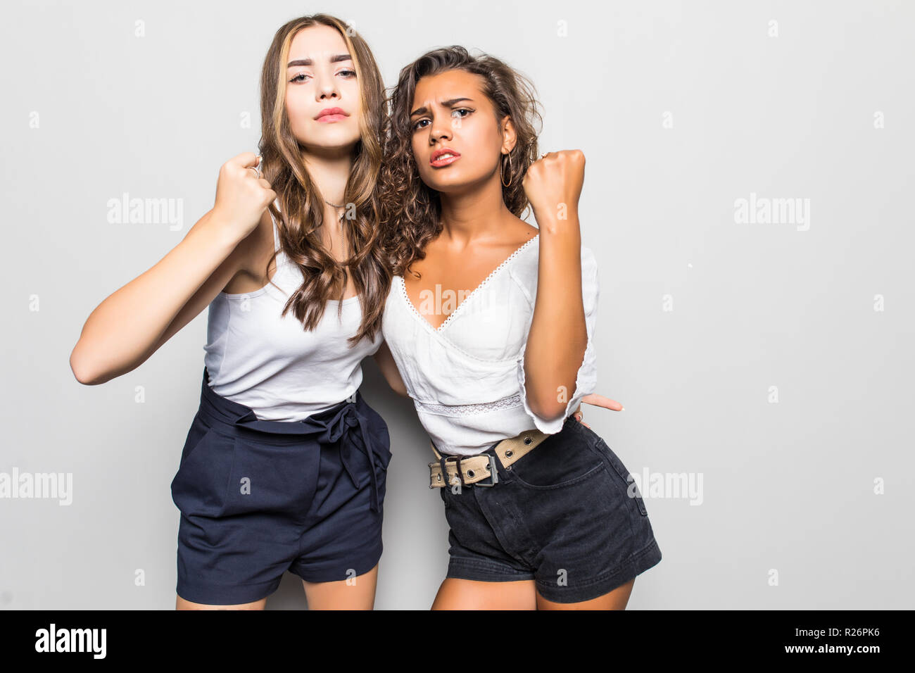 Two angry women hugging to each other while showing their fists and ...