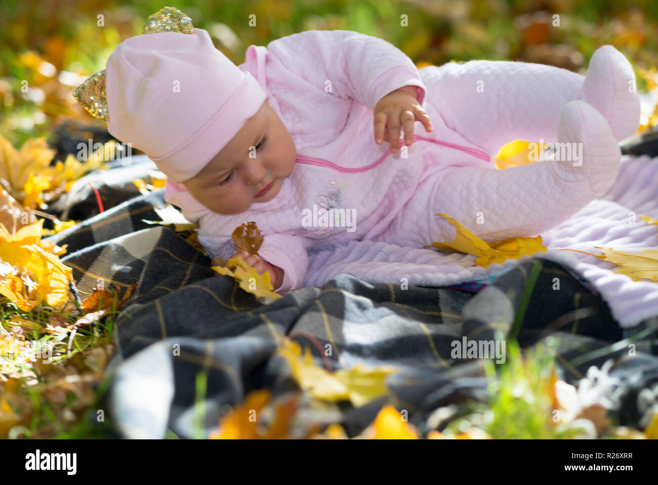 Little baby girl falling over as she catches colorful autumn leaves ...