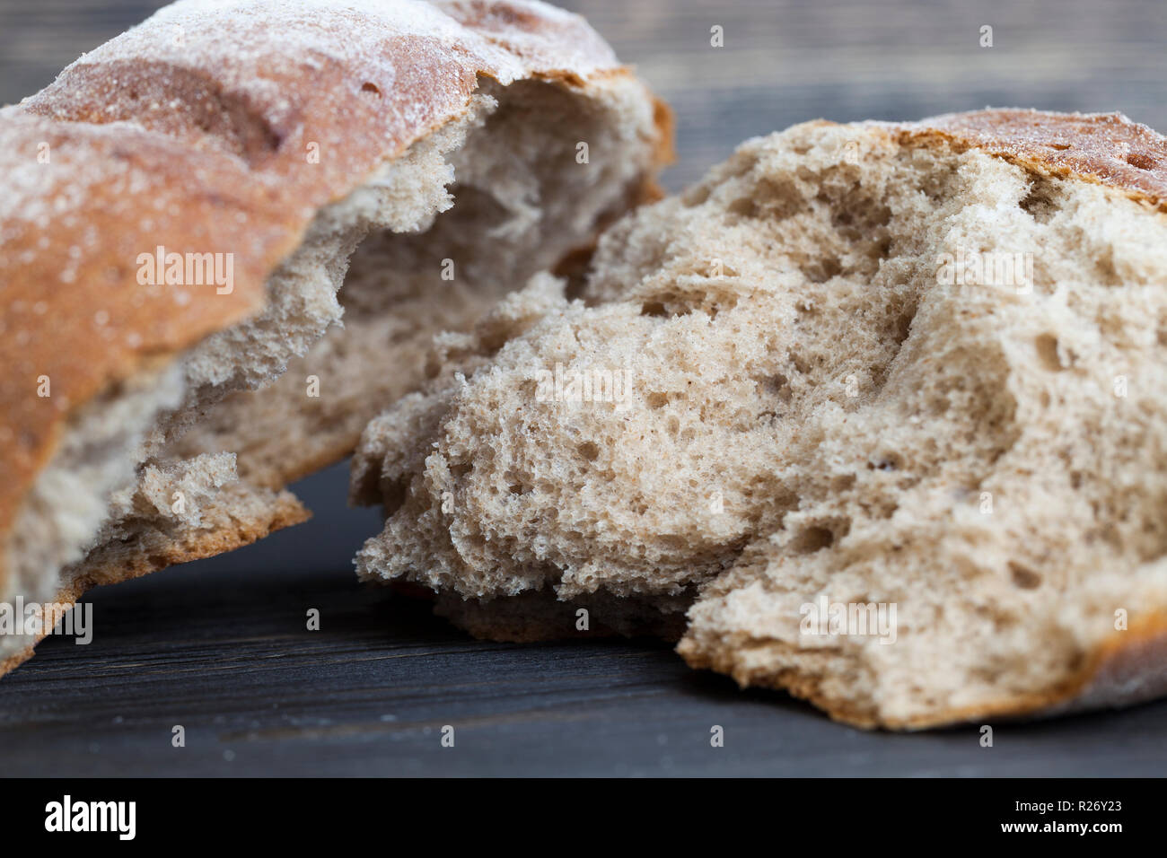 broken light loaf of bread on a wooden table Stock Photo - Alamy