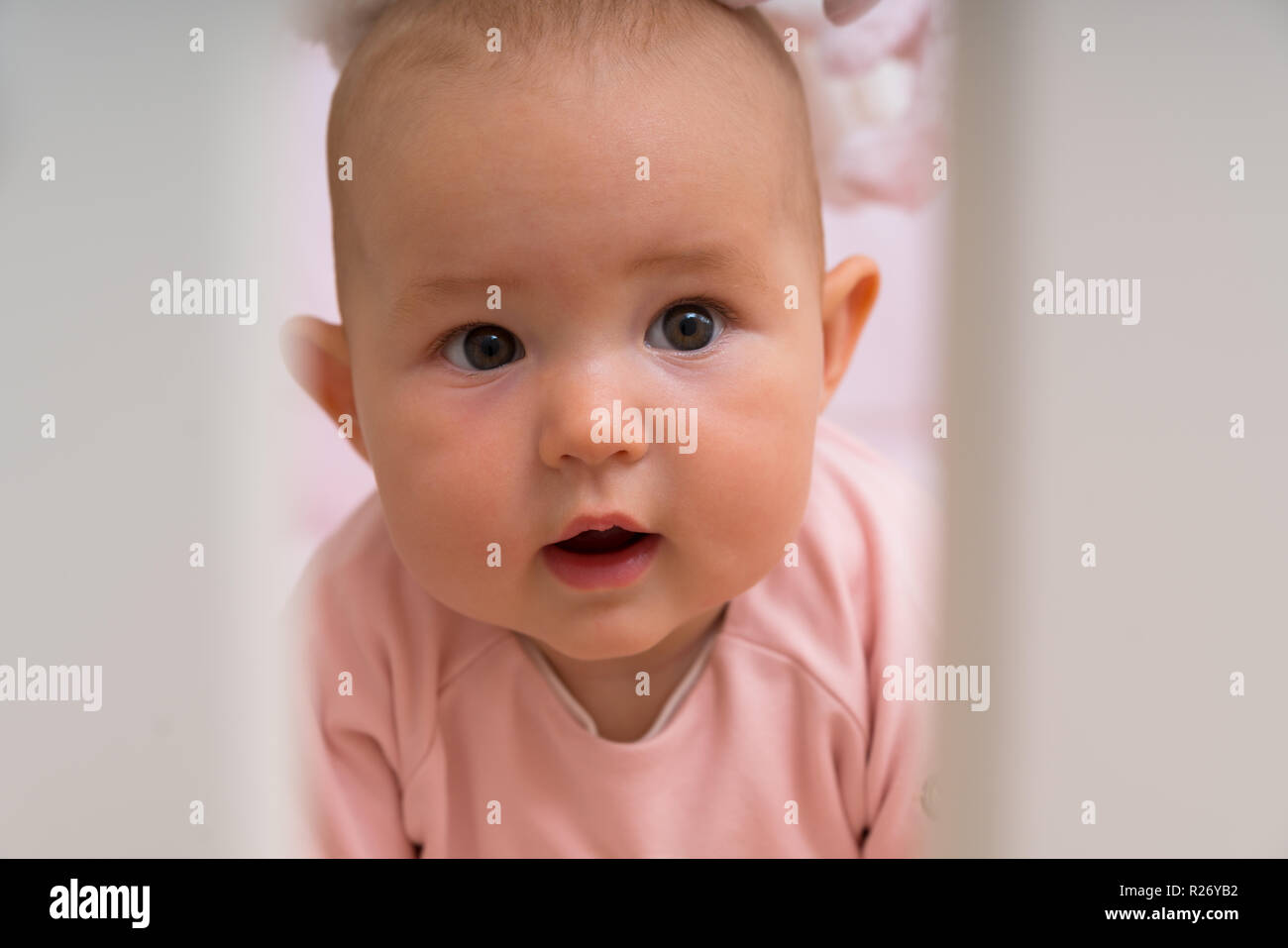 Little girl staring curiously at the camera from between the wooden ...