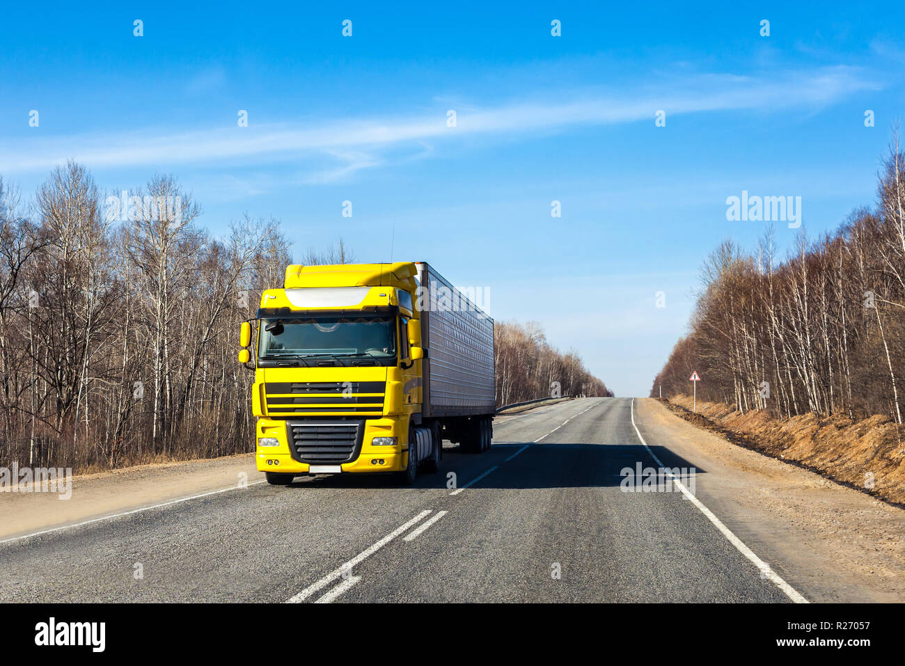 Yellow truck on a road in early spring Stock Photo - Alamy